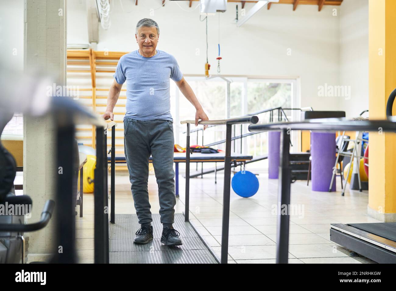 Portrait of smiling senior man exercising on ramp in room at ...