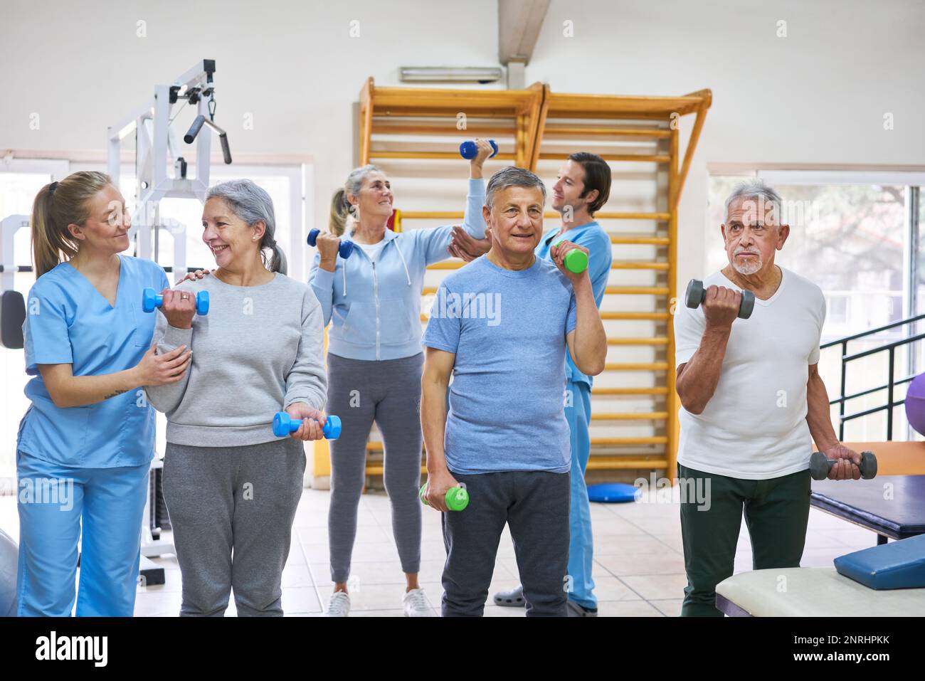 Physiotherapists assisting senior men and women in exercising at ...