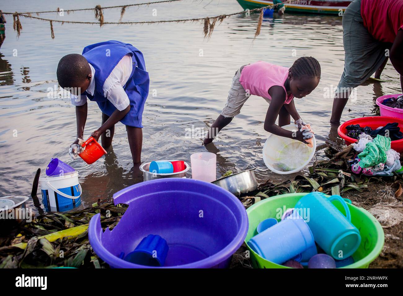 Girls washing cooking utensils, in the fishing village of Kolunga ...