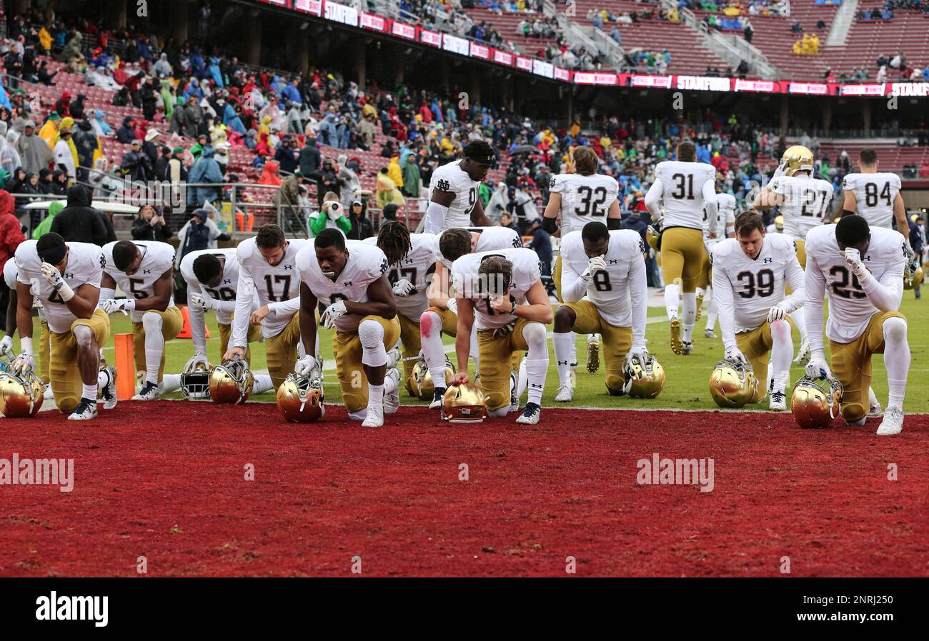 Notre Dame Fighting Irish players kneel in prayer in the enz zone before an NCAA college ...