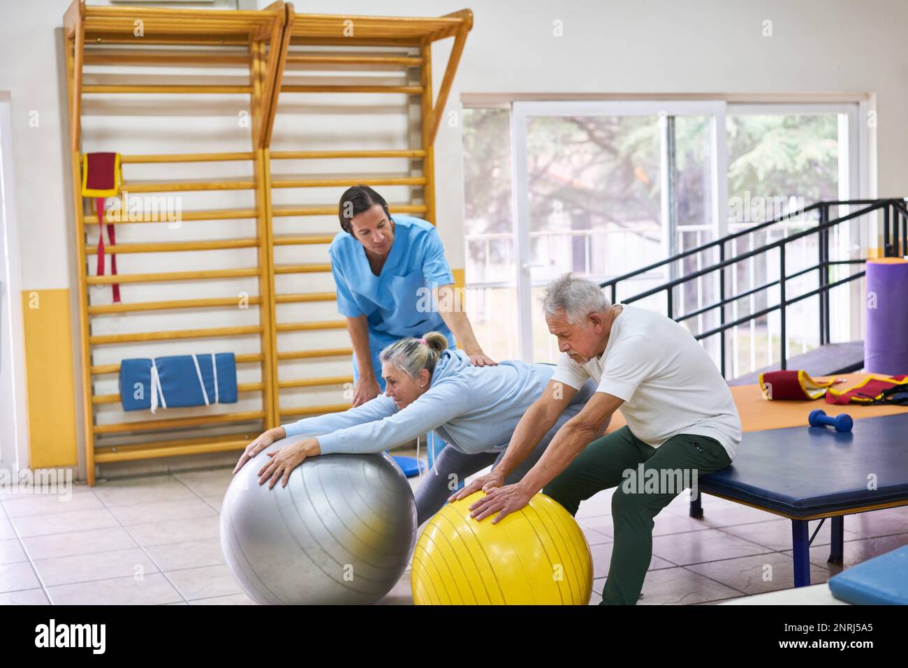 Senior woman and man with physiotherapist guiding in exercise on ...
