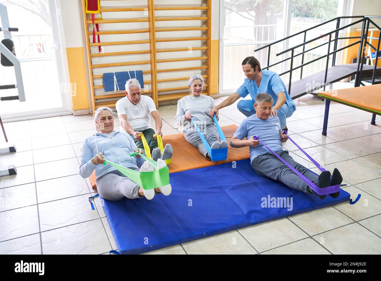 Instructor with group of senior patients doing workout with resistance ...