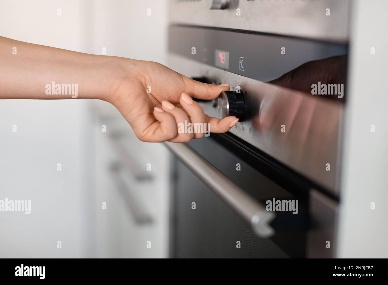 Woman turning on oven hi-res stock photography and images - Alamy