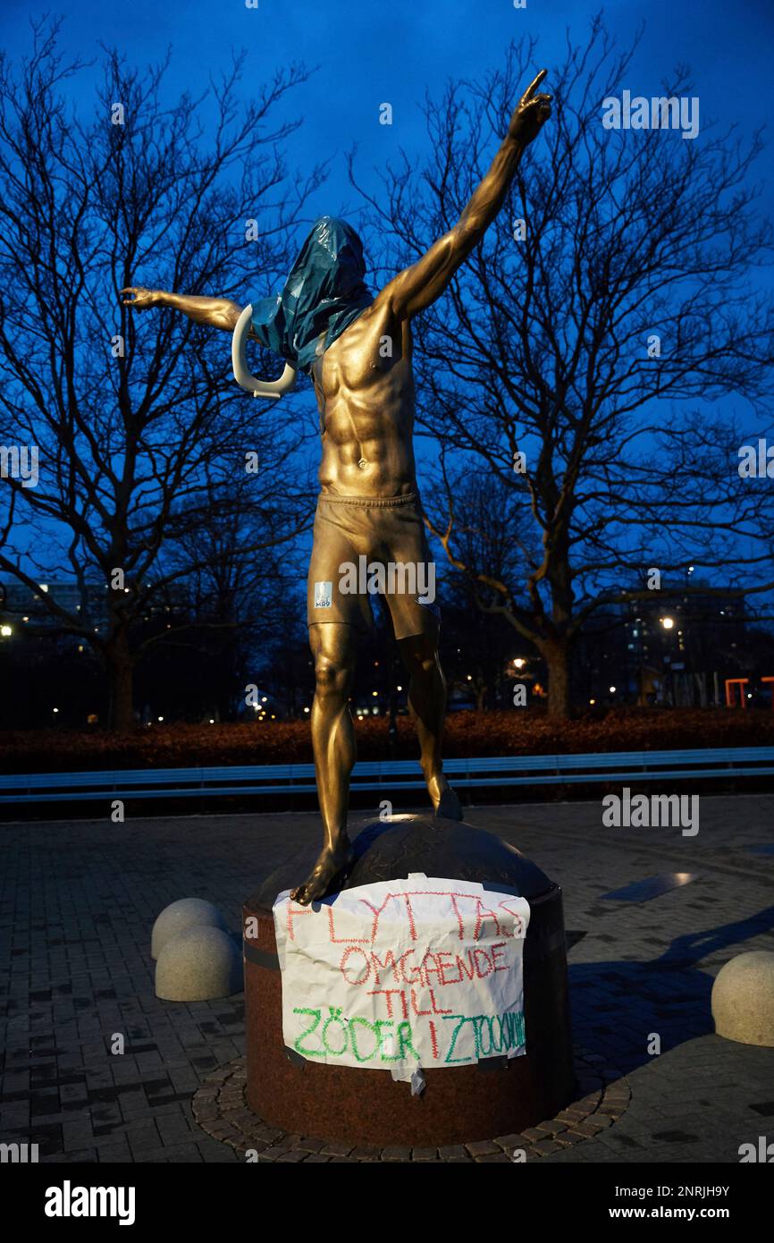 A blue plastic bag and a toilet seat hangs from the statue of the ...