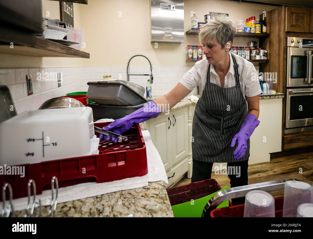 Steam rises into the face of Tami Maguire as she takes clean dishes out ...