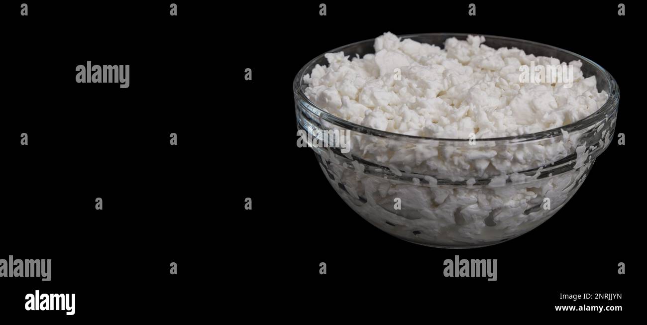 Cottage cheese in glass bowl isolated on black background. Side view of ...