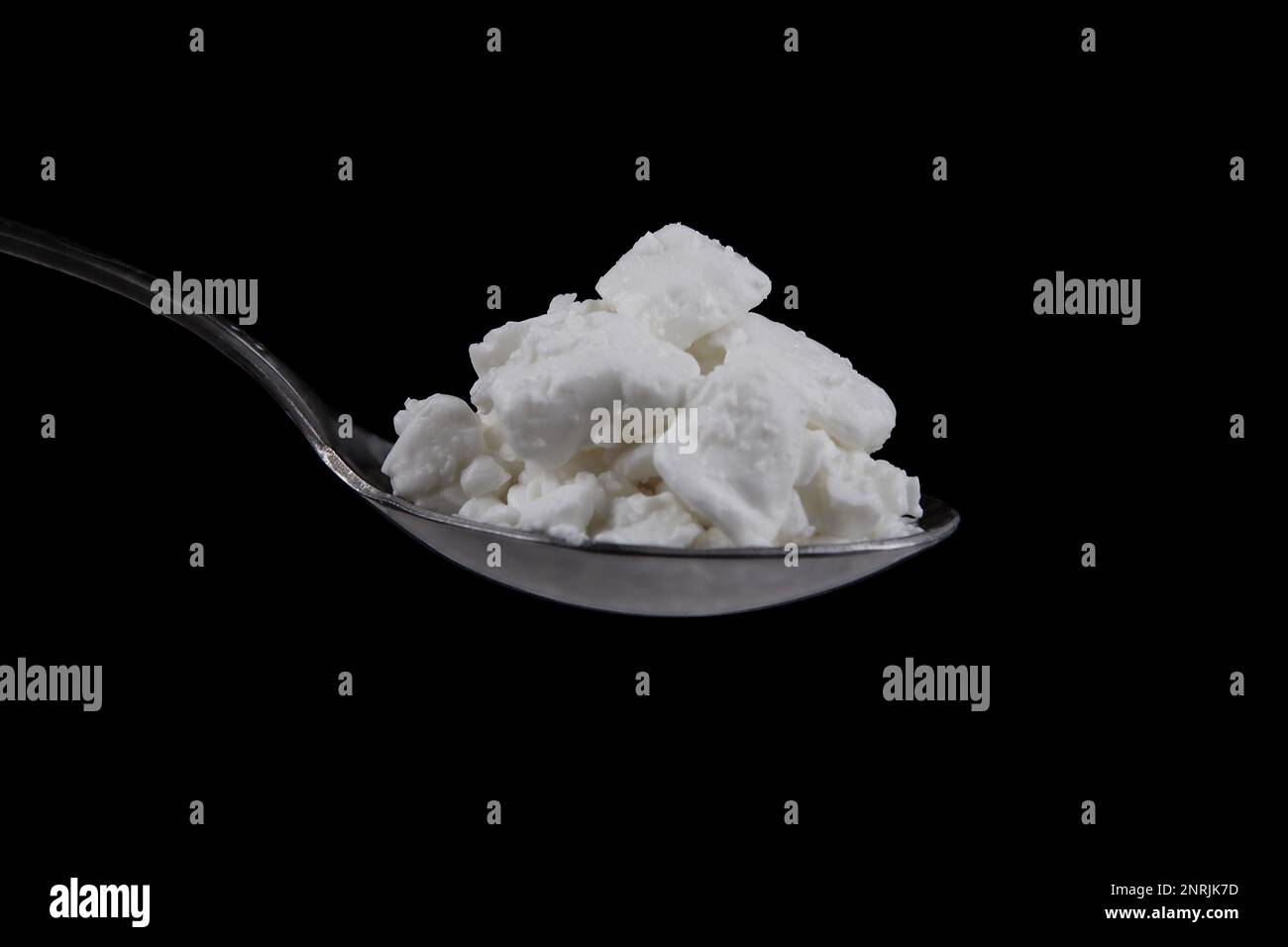 Cottage cheese in metal spoon isolated on black background. Side view ...