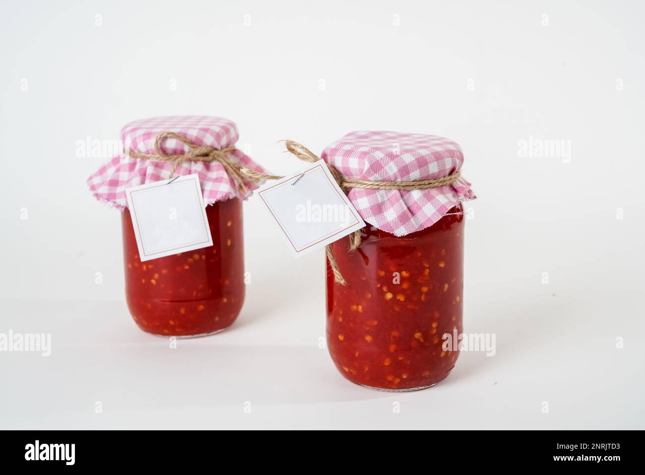 Two canned homemade tomato paste jars with empty labels isolated on ...