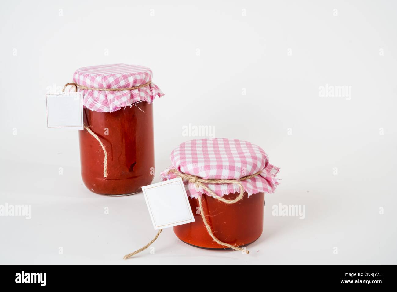 Two canned homemade tomato paste jars with empty labels isolated on ...