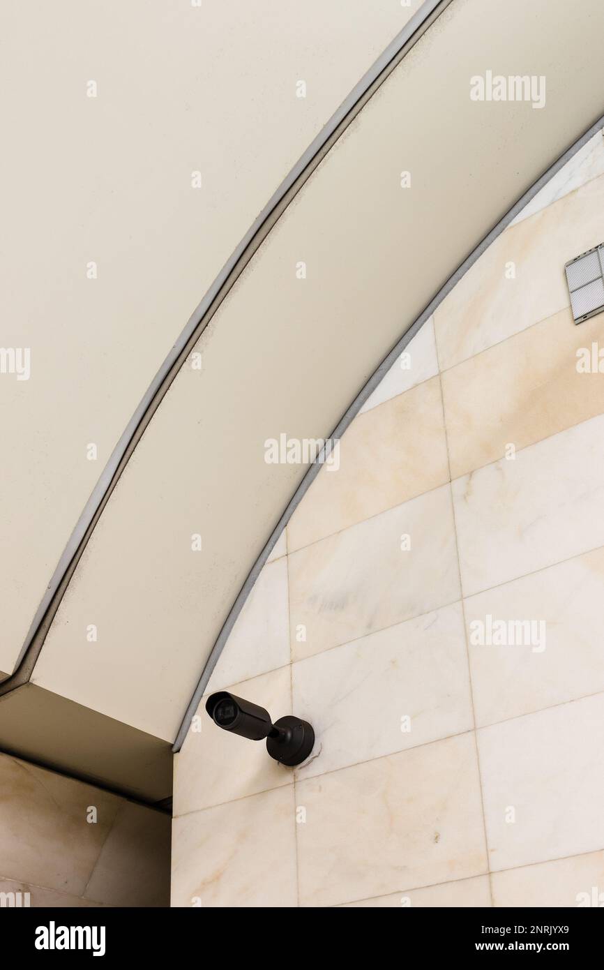 bottom view of black surveillance cctv camera on tiled wall in ...