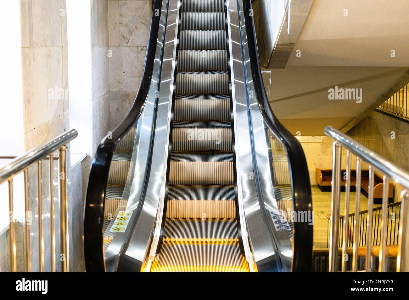 front view of indoor moving escalator with yellow electric backlight ...