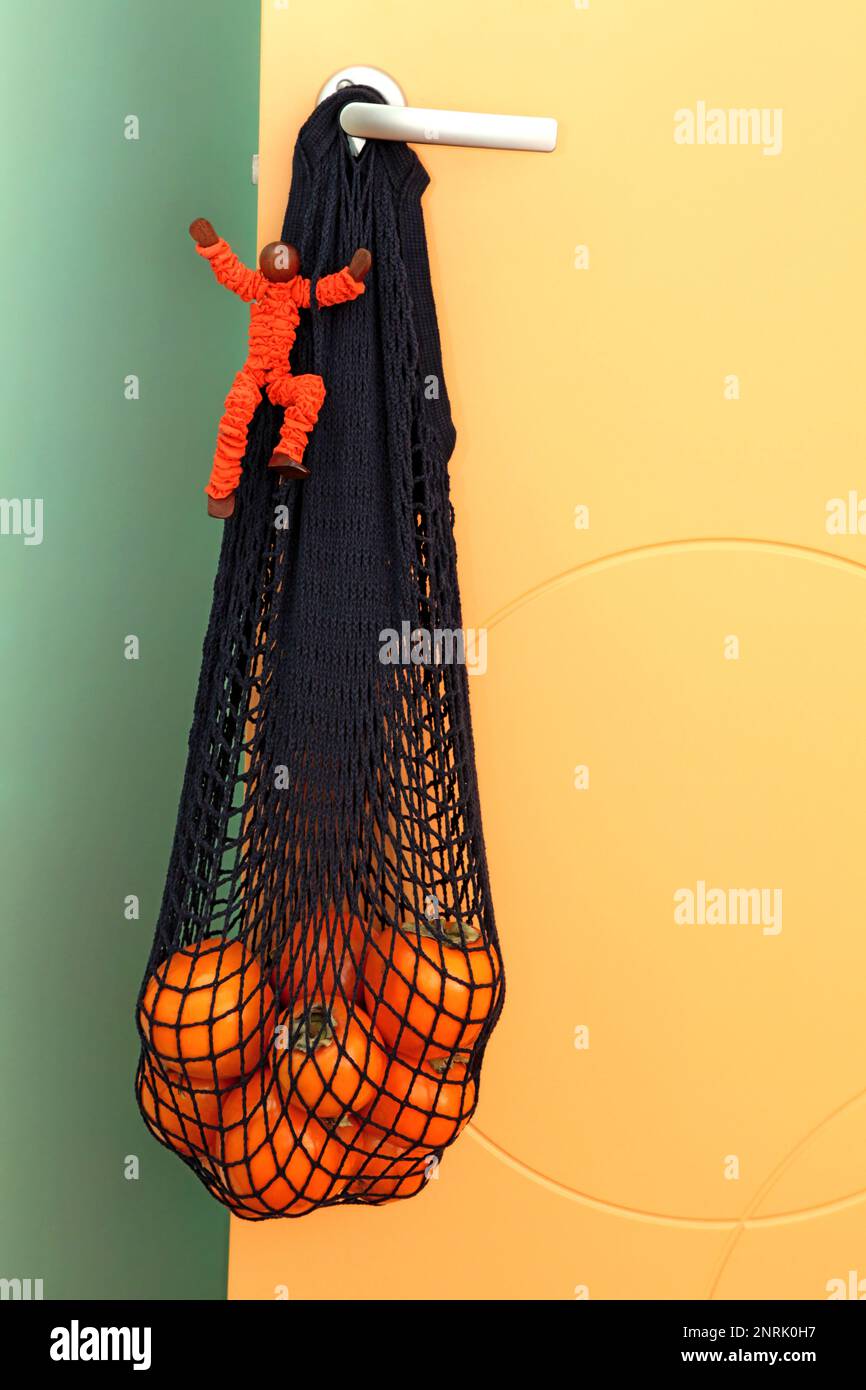 This image is a stock photo of an orange sitting inside a net hanging ...