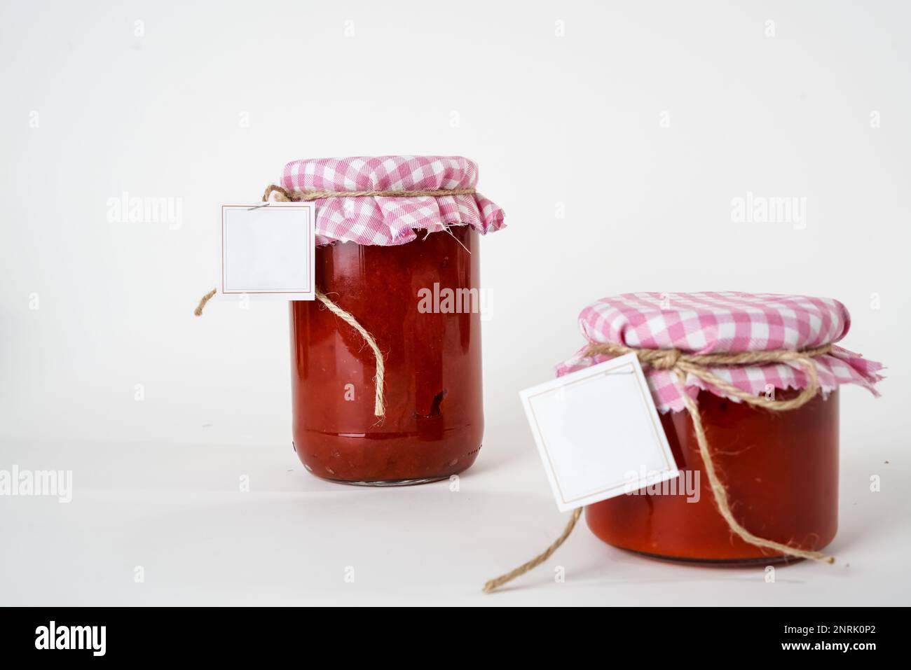 Two canned homemade tomato paste jars with empty labels isolated on ...