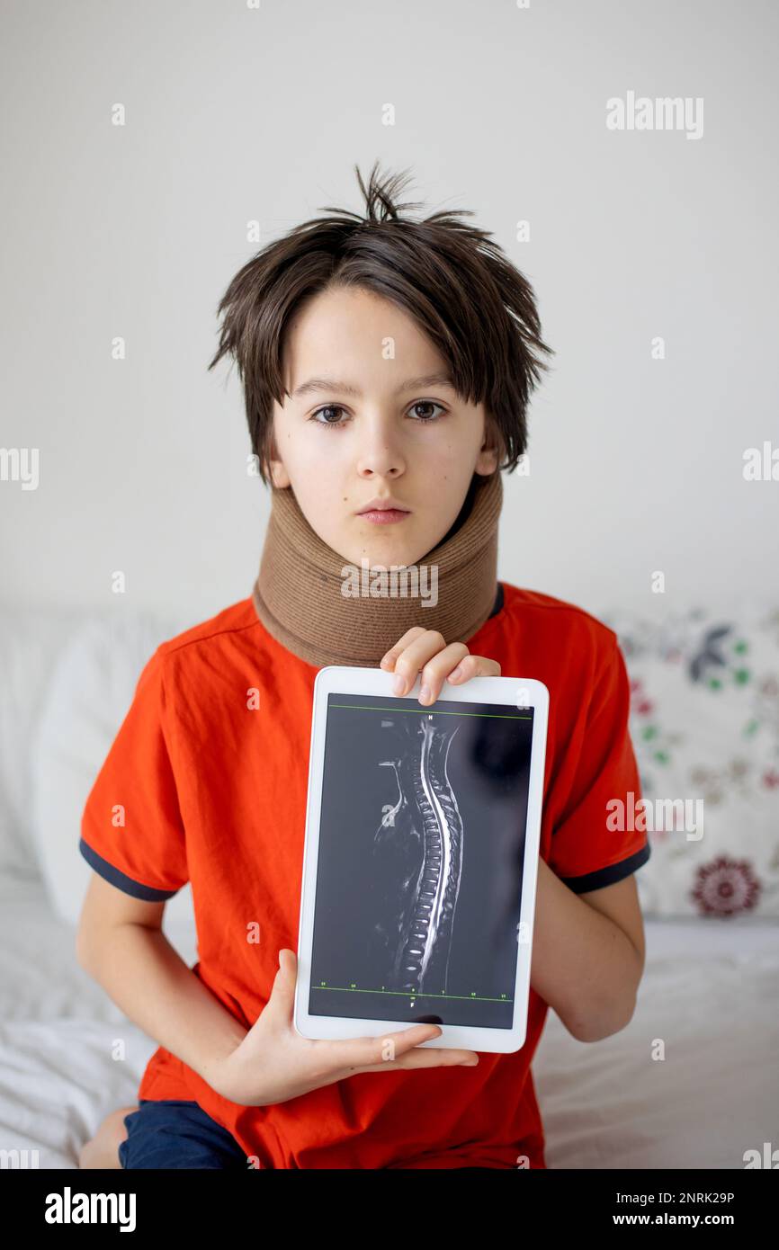 Preteen child, boy, holding tablet with picture of fractured thoracic ...