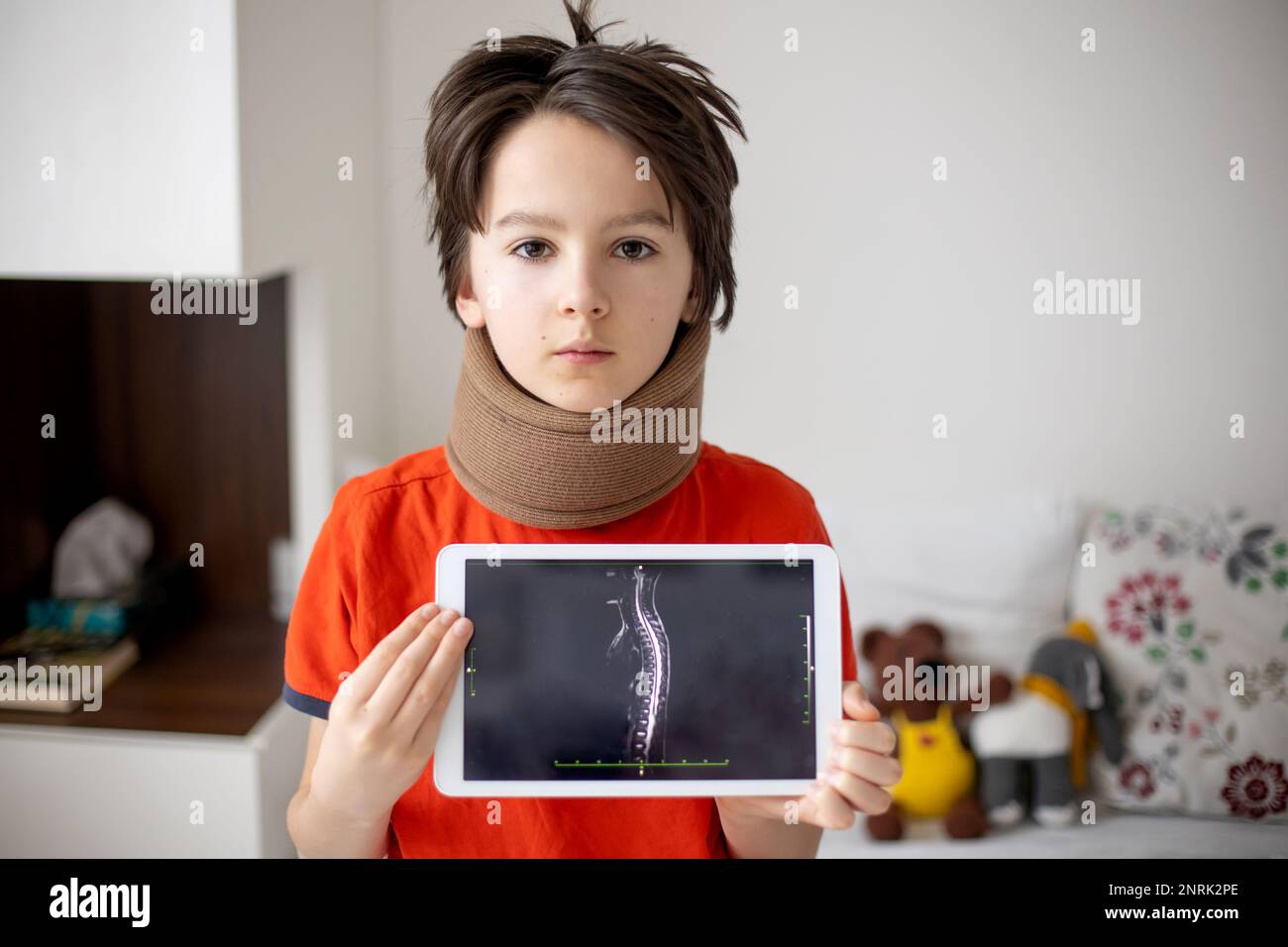 Preteen child, boy, holding tablet with picture of fractured thoracic ...