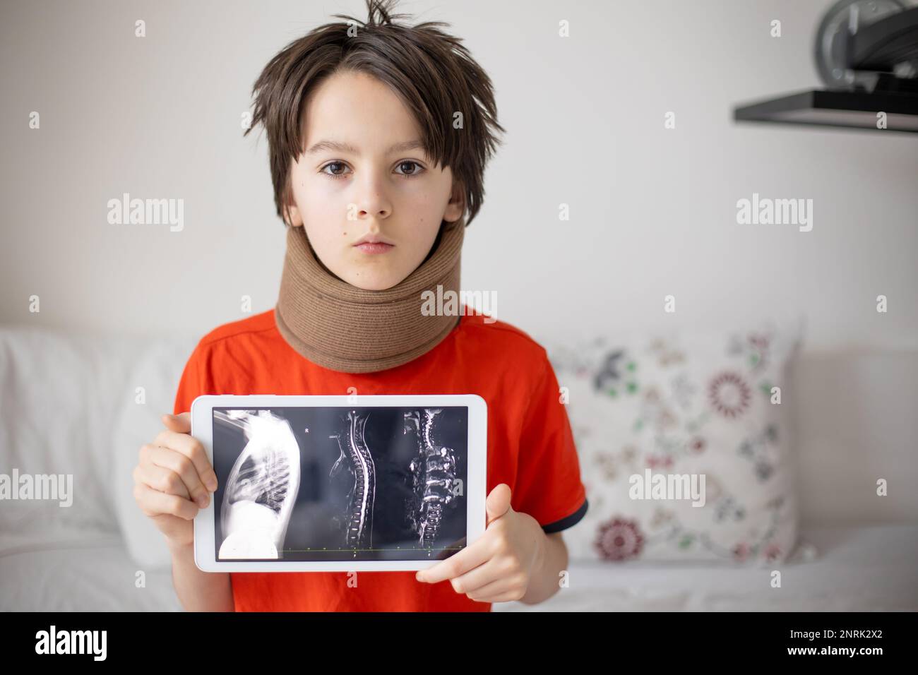 Preteen child, boy, holding tablet with picture of fractured thoracic ...