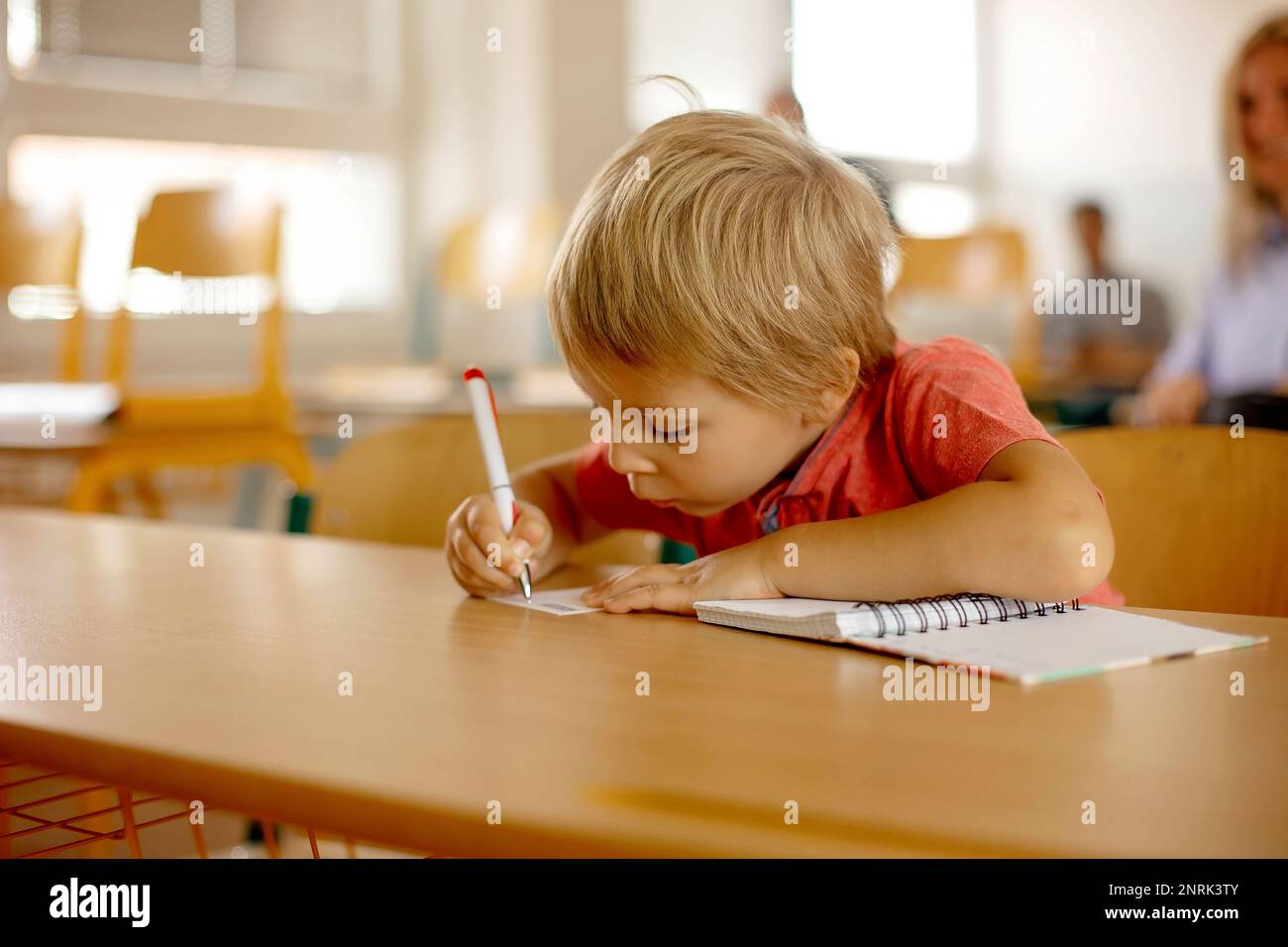 Preschool child, sitting on a desk at school, having lesson, learning ...
