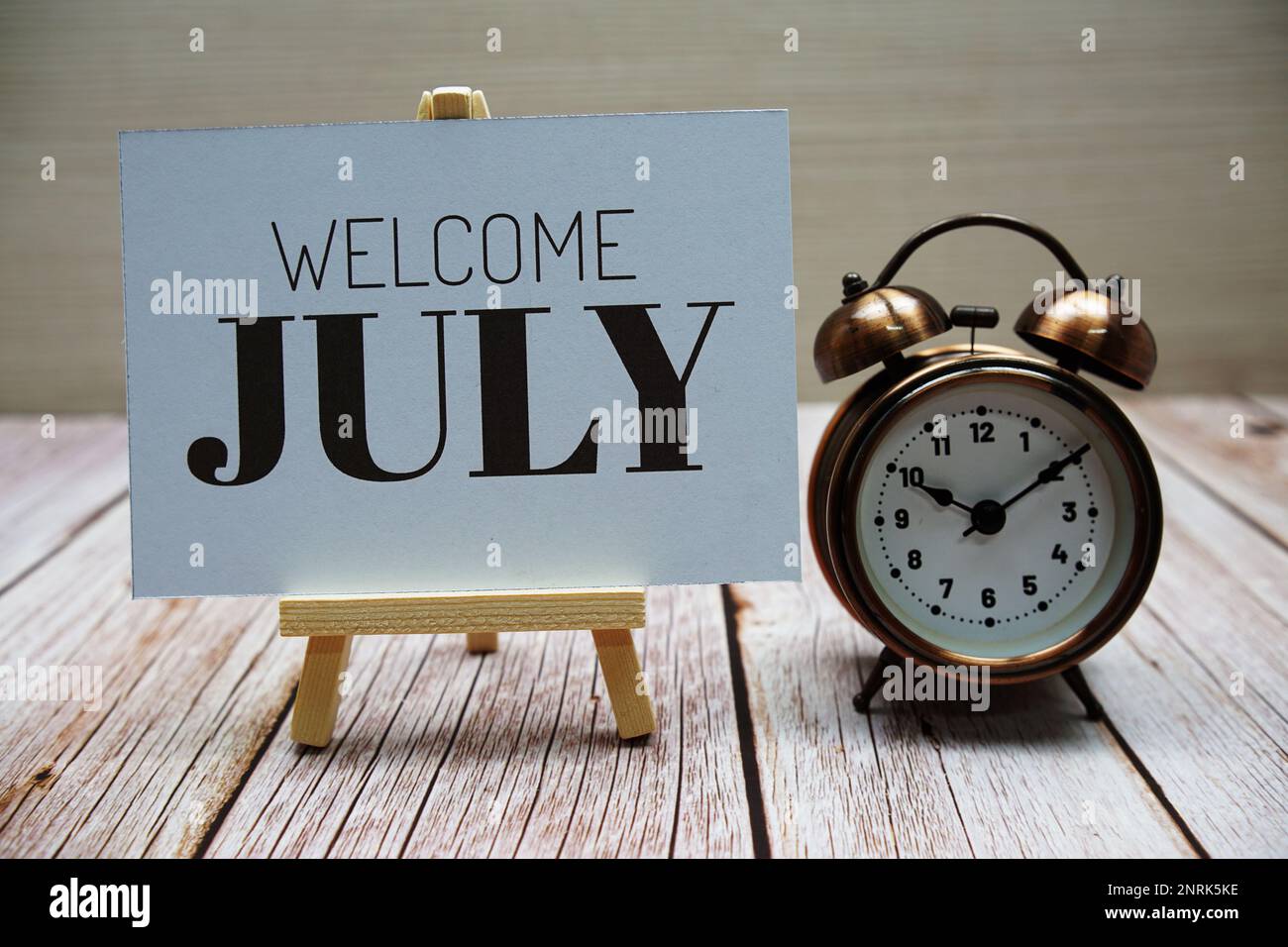 Welcome July text message with alarm clock on wooden background Stock ...