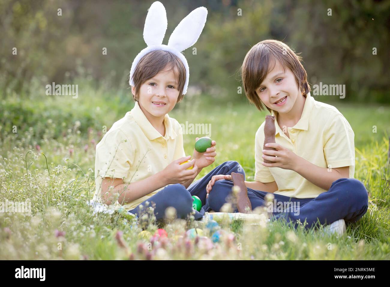 Sweet children, boy brothers with bunny ears, egg hunting for Easter ...