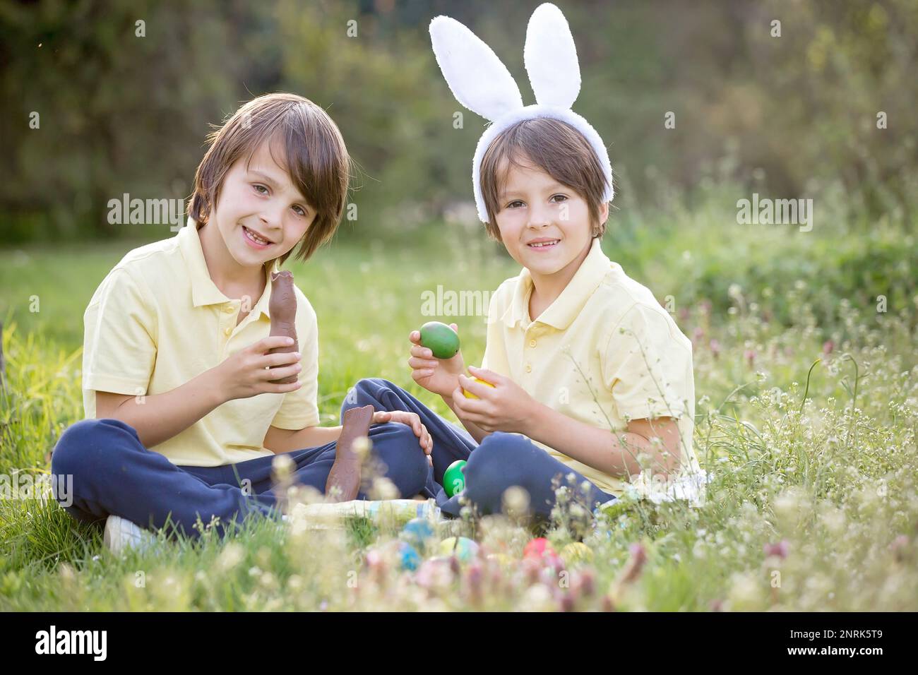 Sweet children, boy brothers with bunny ears, egg hunting for Easter ...
