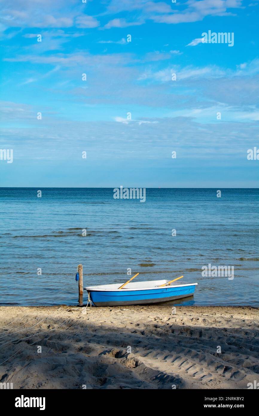Small blue boat anchors on the beach in front of the open sea with blue ...