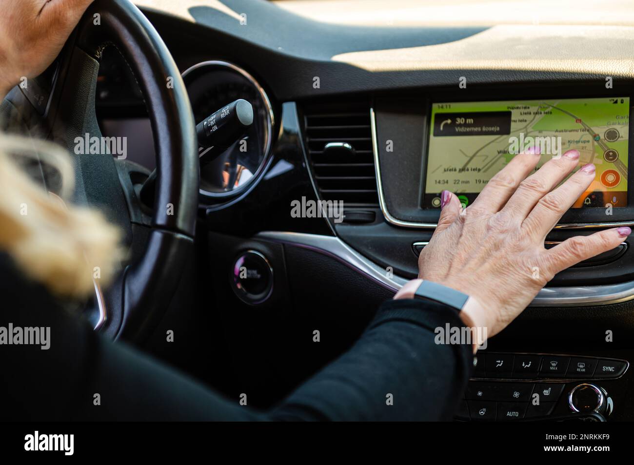 woman driving car, presses finger on touch screen, using car navigation ...