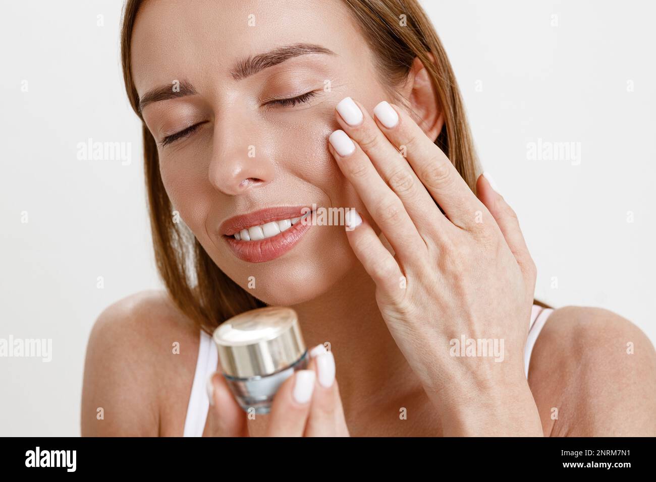 Close up face portrait of young woman applying cream to her face on ...