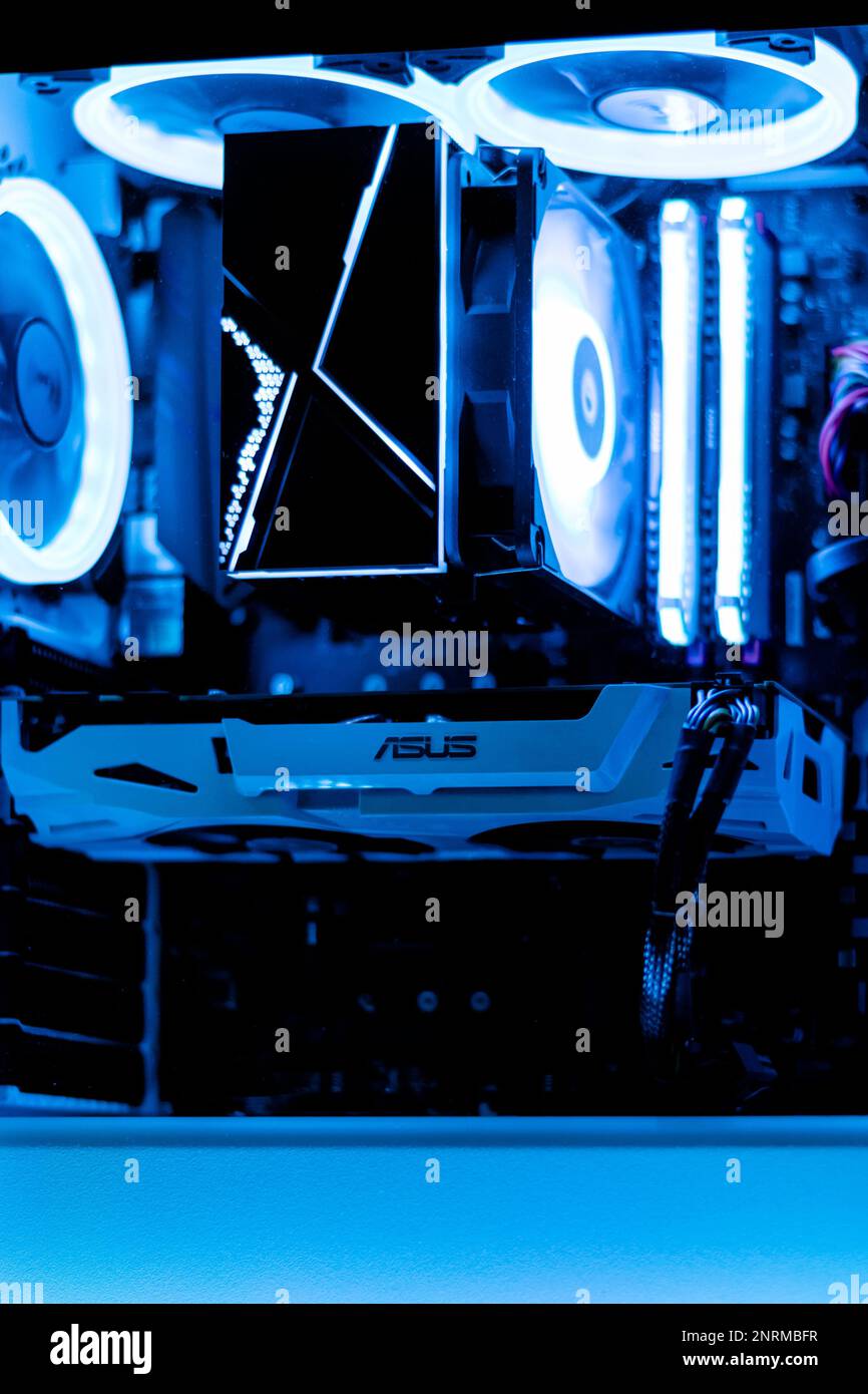 An ASUS computer on a desk, with a cooling fan providing ventilation ...