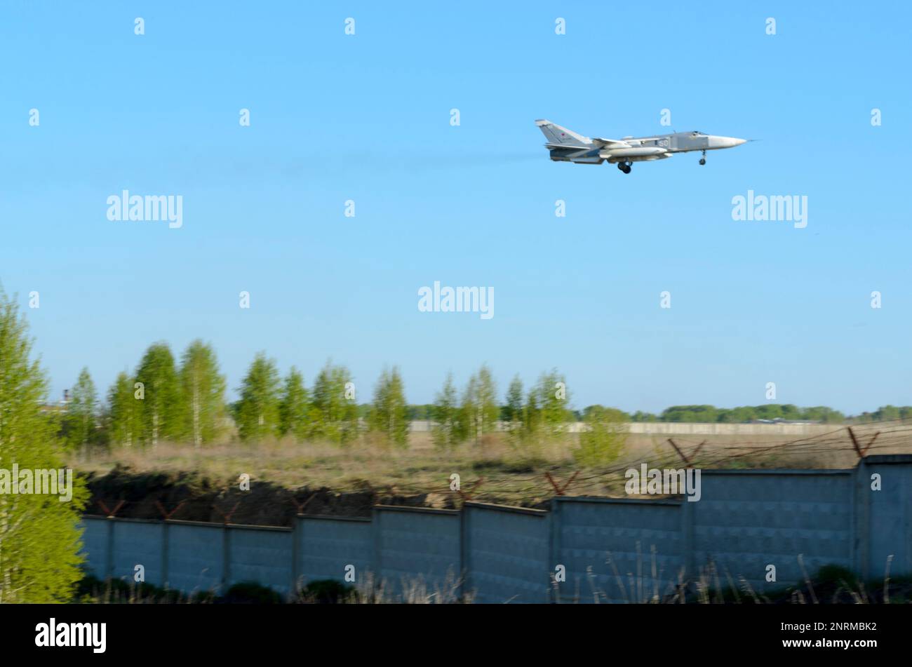 Plane view from below in the blue sky near the fence with barbed wire ...