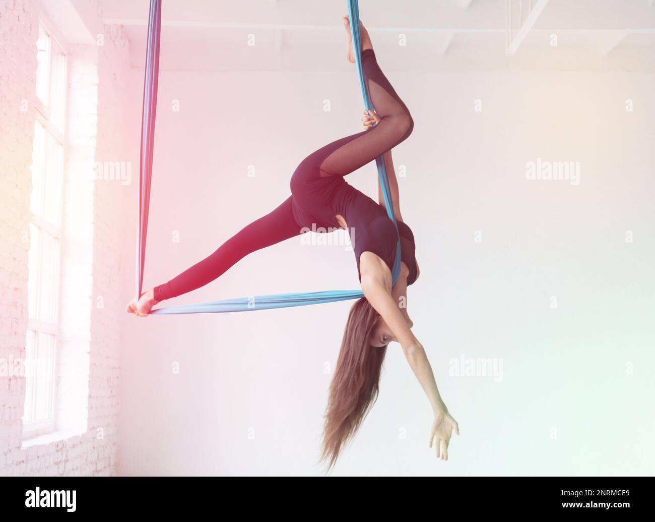 Fit young woman doing gravity fly yoga asana stretching exercises in ...