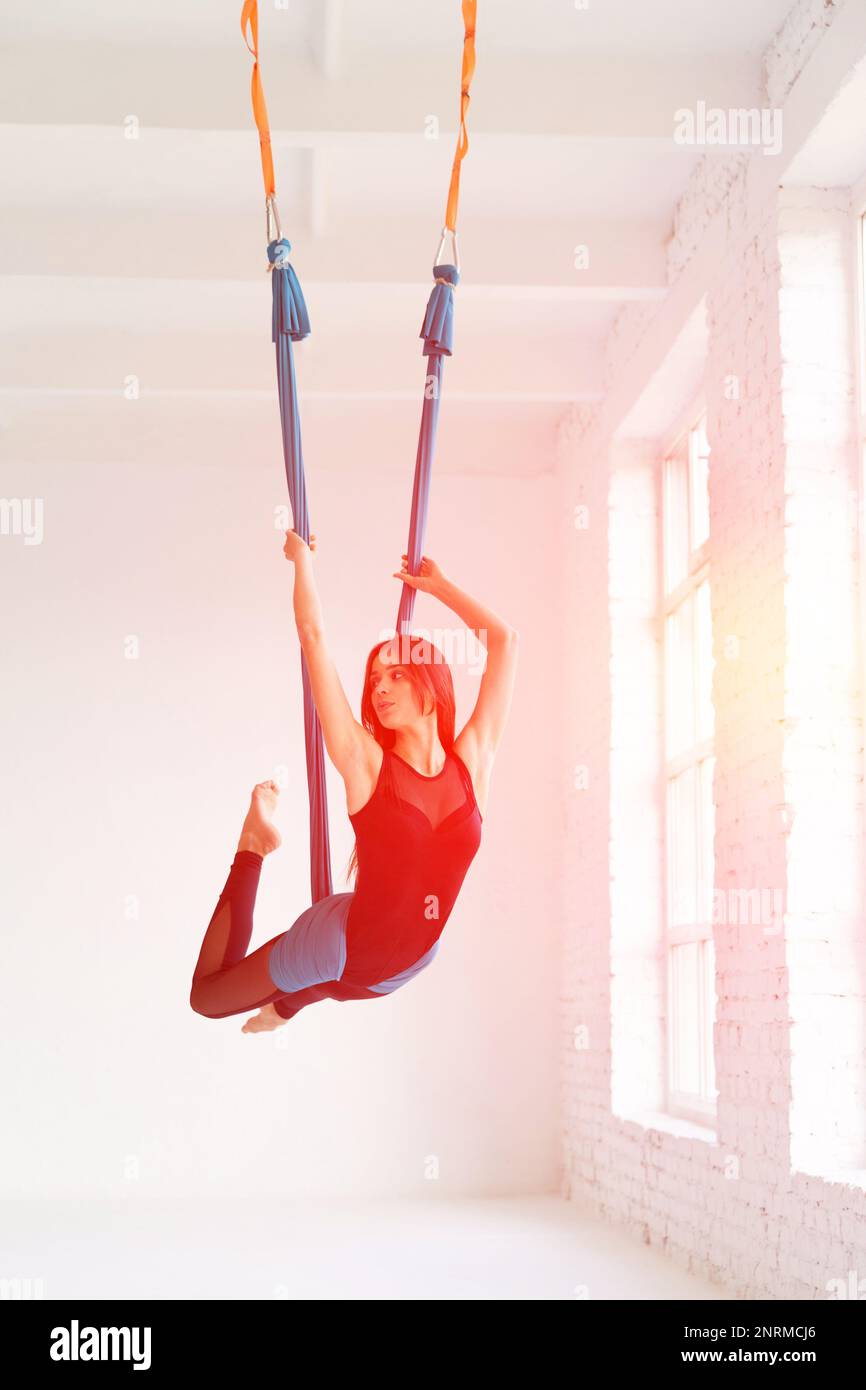Fit young woman doing anti gravity fly yoga asana stretching exercises ...