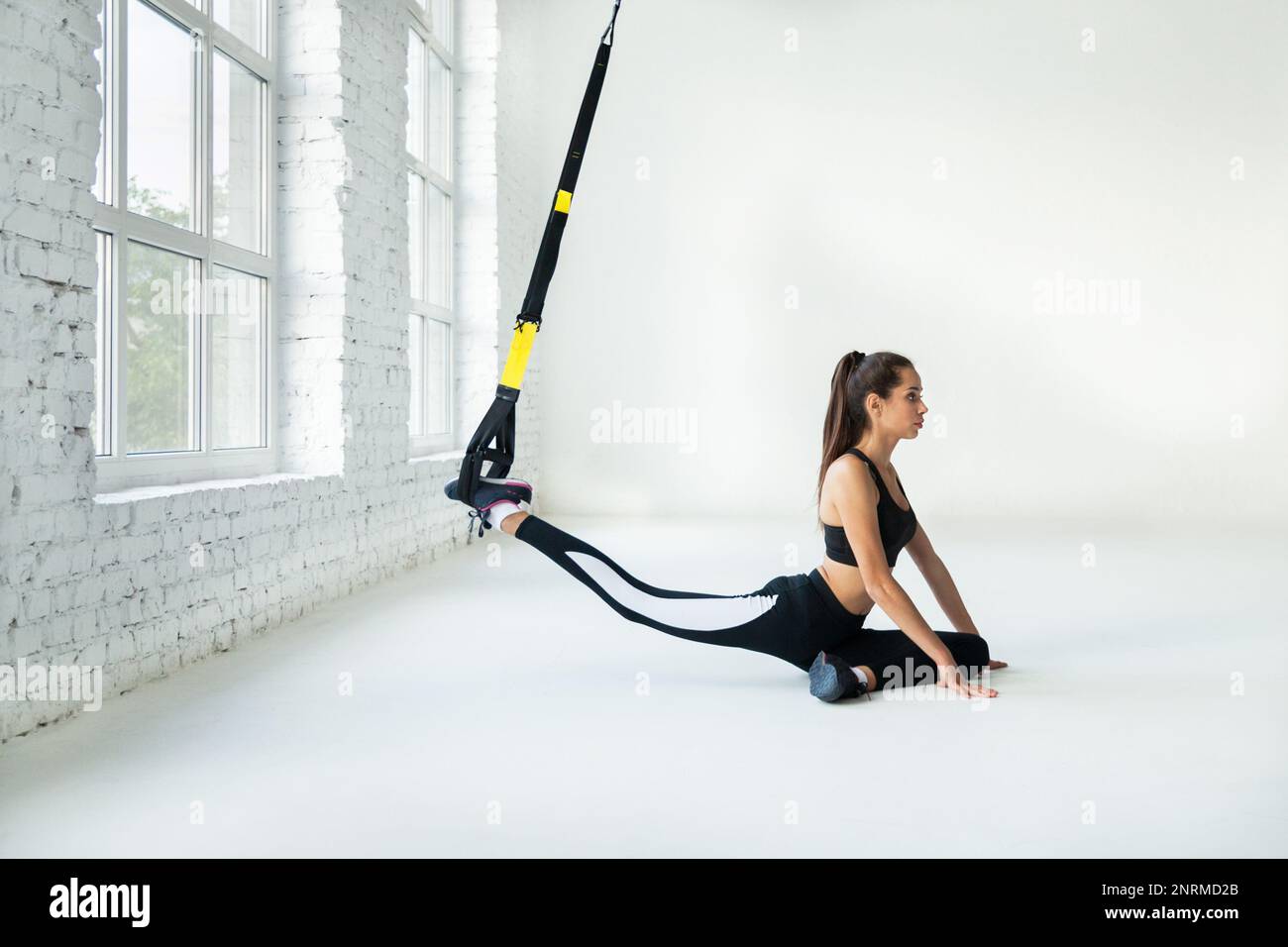 Fit pretty young woman doing fly yoga stretching exercises with trx fitness straps in fitness ...