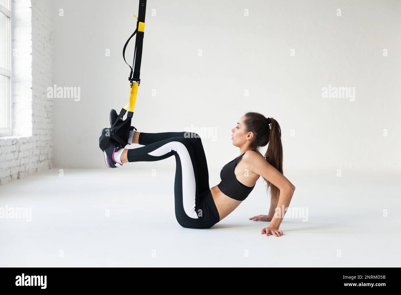 Fit pretty young woman doing fly yoga stretching exercises with trx fitness straps in fitness ...