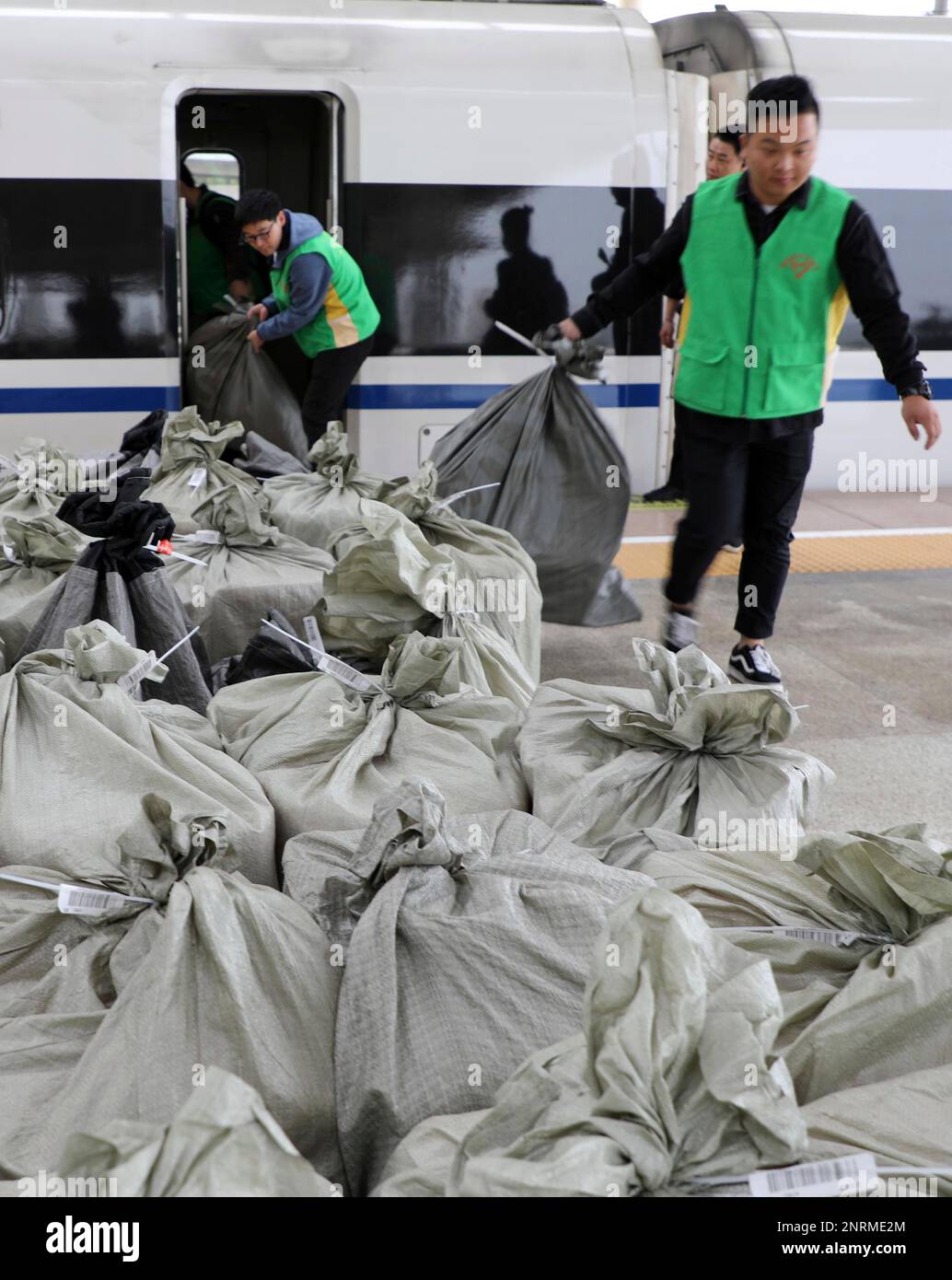 Railway workers load bags of parcels off a bullet train at a railway ...