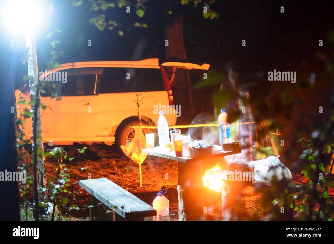 A campfire burns in the night at the tourist Park with things that are ...