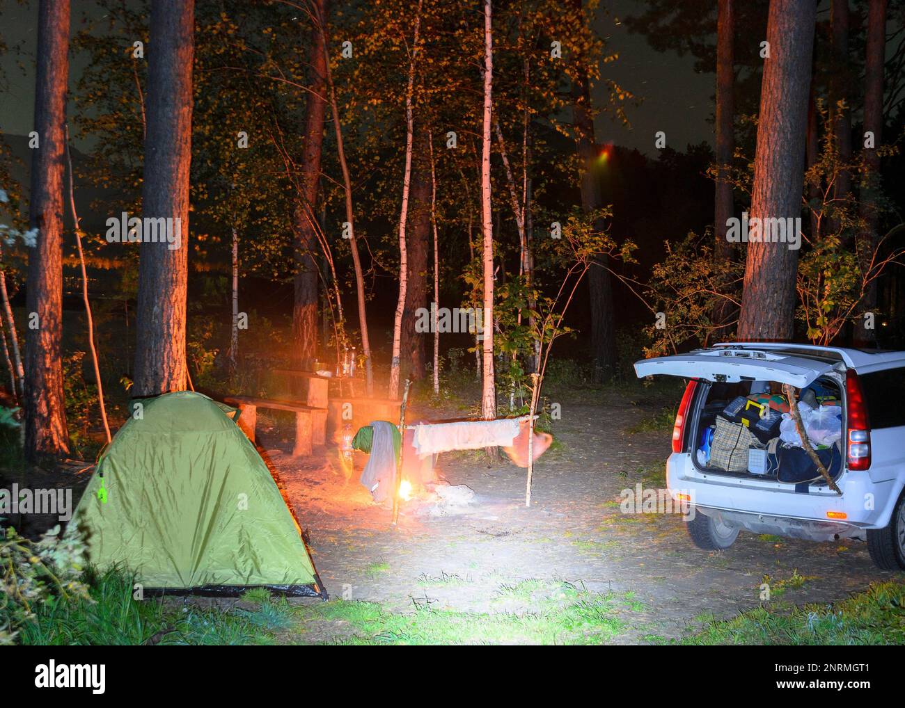 A campfire burns in the night at the tourist Park with things that are ...
