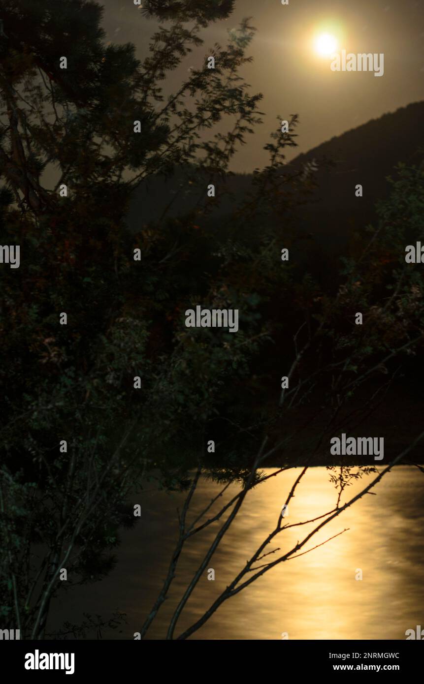 The light of the moon over the mountain is reflected in the water of ...