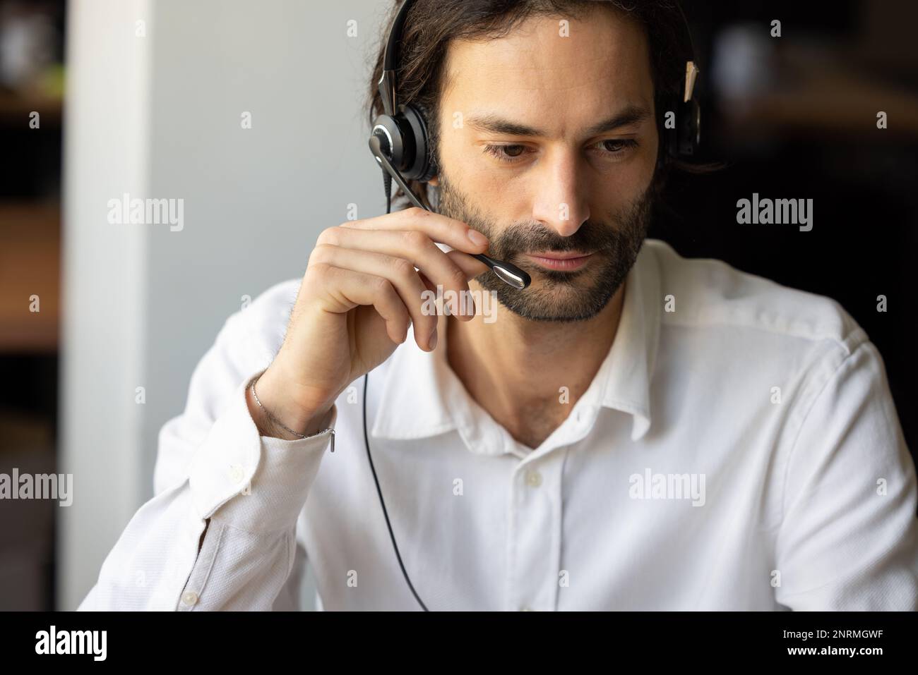 portrait of a young TV adviser. He wears a headset and answers phone ...