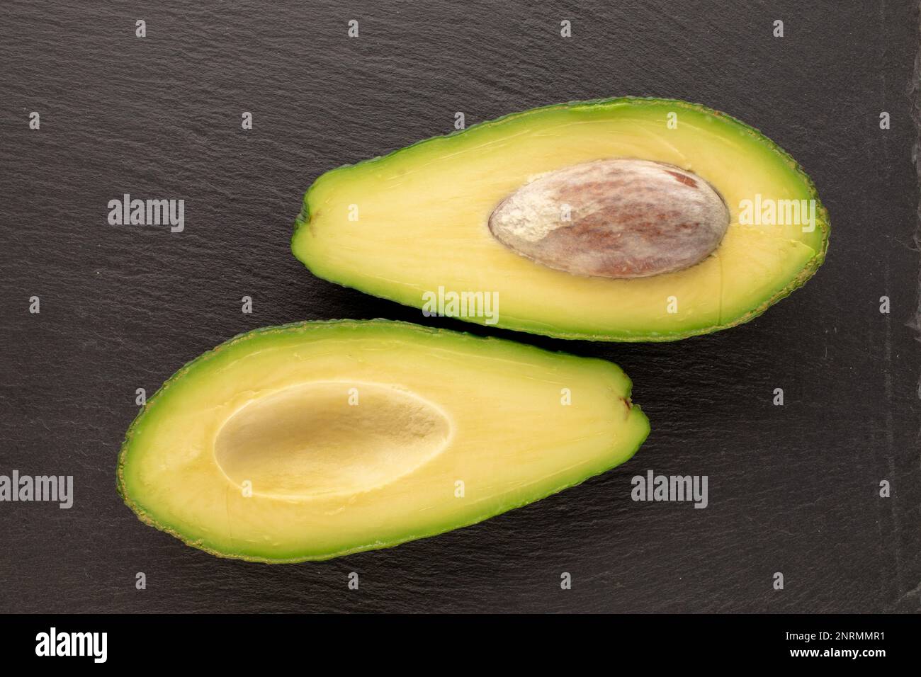 Two halves of organic avocado on a slate stone, macro, top view Stock ...
