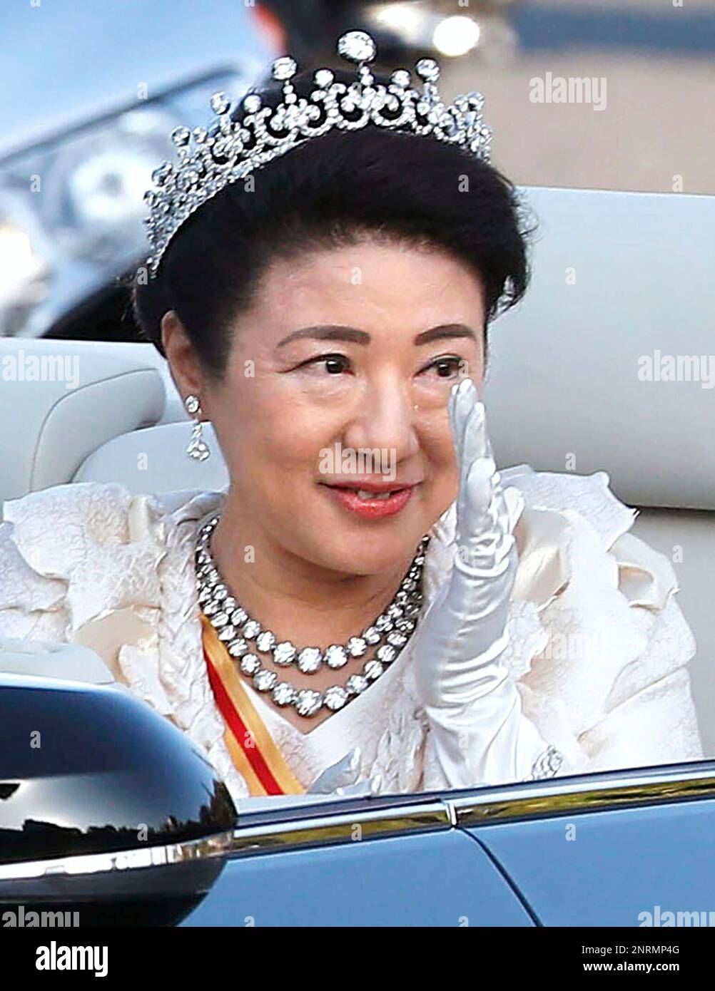 Japan's Empress Masako greets well-wishers from an open car in a parade ...