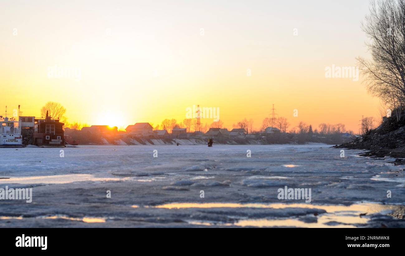 Two fishermen in the distance on the melting ice in the spring in the ...