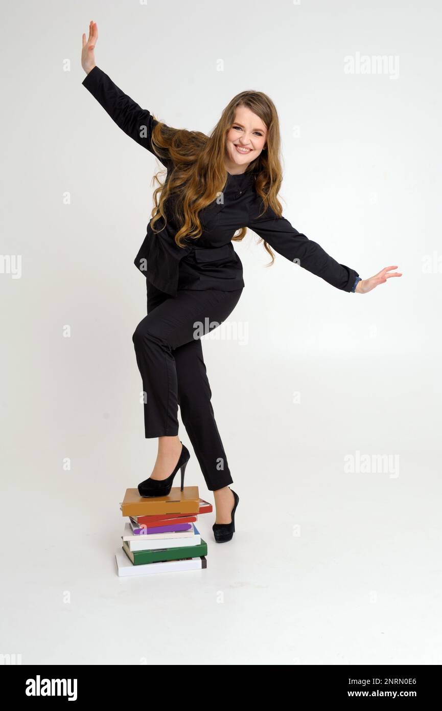 girl graduated from university she stands in high-heeled shoes on books ...
