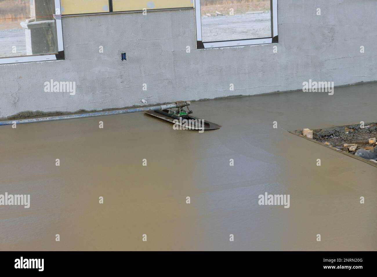 Following pouring of concrete worker plasters wet concrete cement floor ...