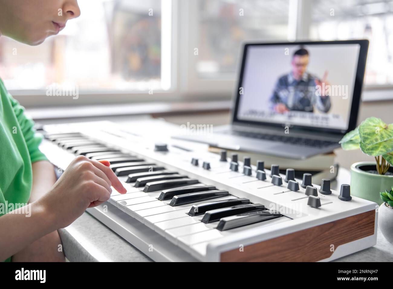 A girl learns to play the piano with a teacher online, remote learning ...