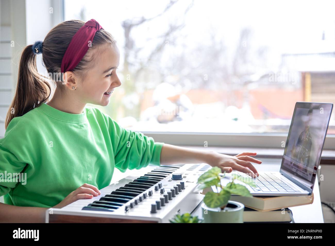 A girl learns to play the piano with a teacher online, remote learning ...