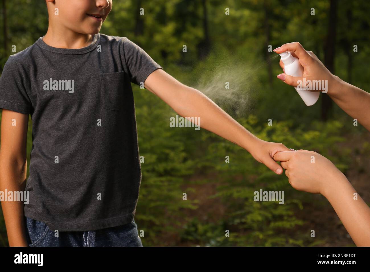 Woman applying insect repellent on her son's arm in park, closeup. Tick ...