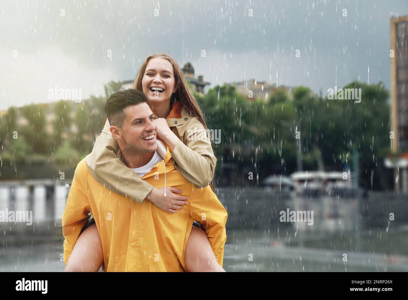 Lovely couple wearing raincoats under rain on city street Stock Photo ...