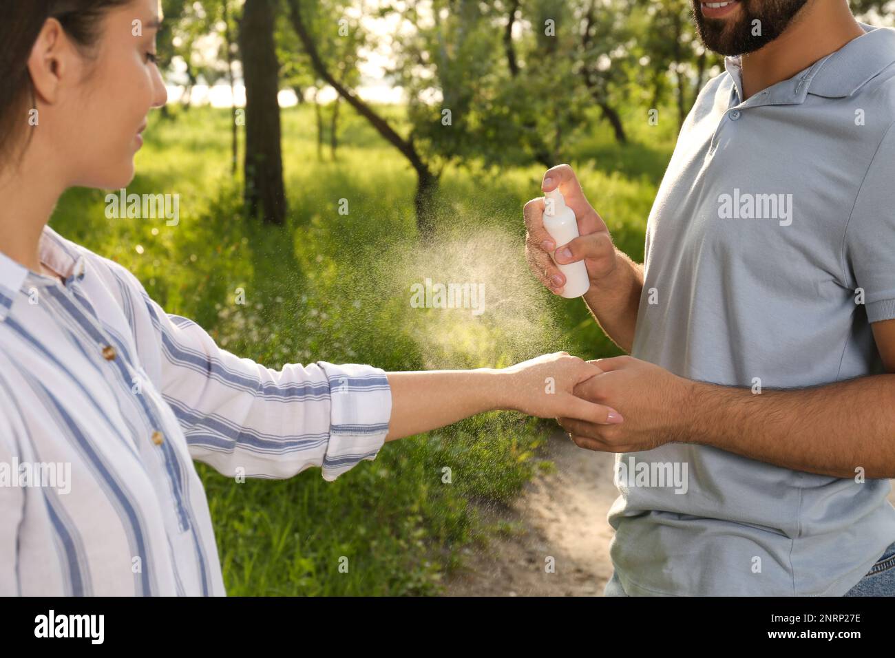 Man applying insect repellent on his girlfriend's arm in park, closeup ...