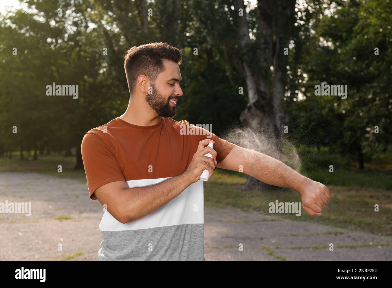 Man applying insect repellent on arm in park. Tick bites prevention ...