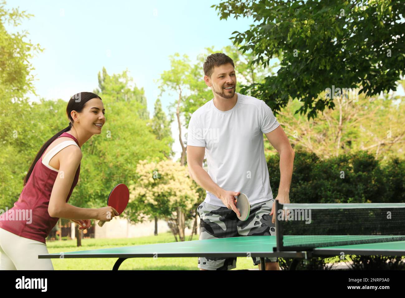 Happy couple playing ping pong in park Stock Photo - Alamy